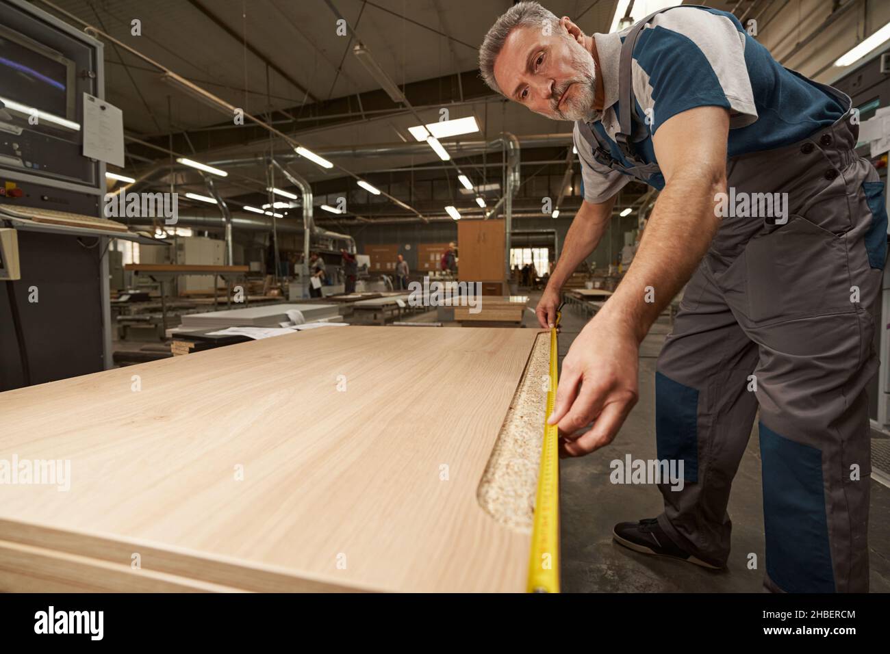 Concentrated male carpenter measuring the length of plank Stock Photo ...