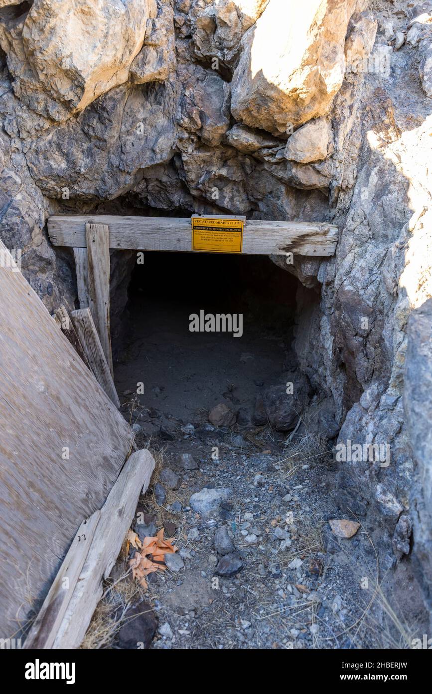 Metal yellow sign warns of registered mining claim above a mineshaft ...
