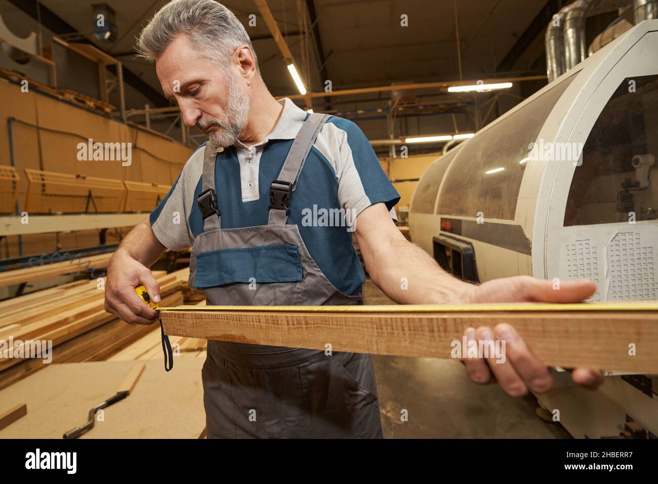 Attentive bearded man measuring length of wood Stock Photo - Alamy