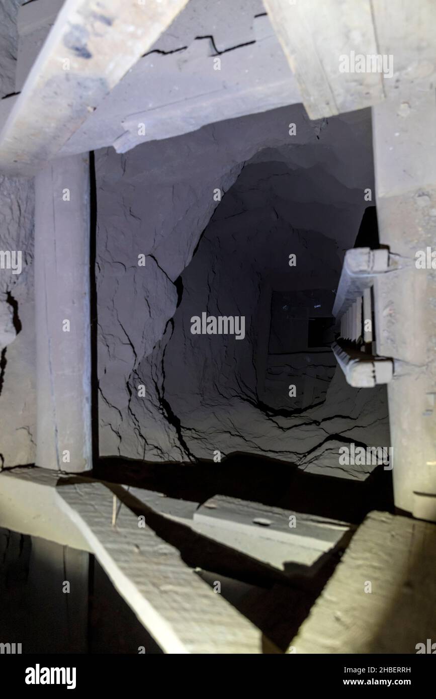 Hand dug hole goes straight into the ground mining shaft with a ladder ...