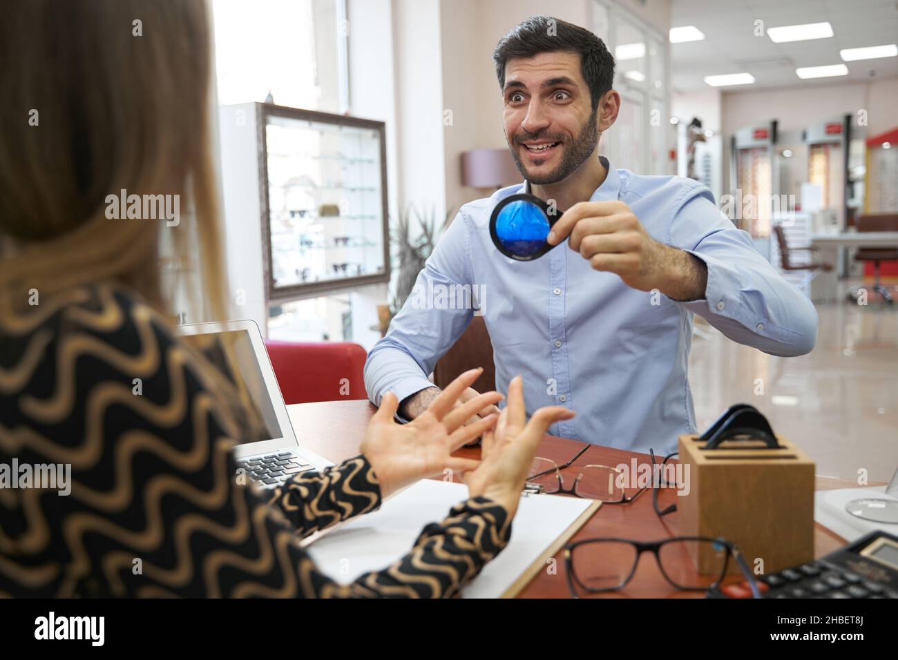 Shocked customer holding optical loupe with blue filling Stock Photo ...