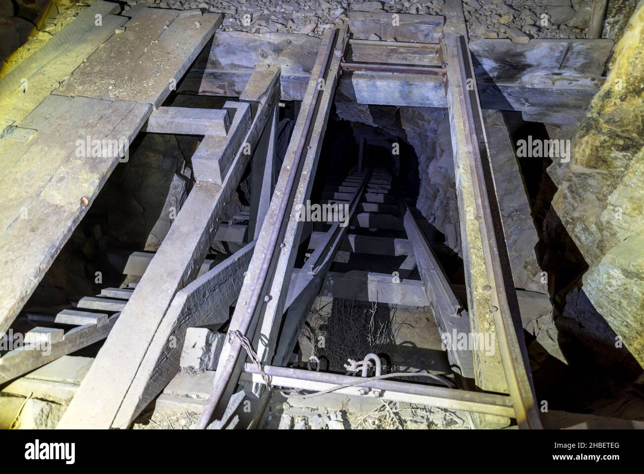 Looking down a mine shaft that contains a wooden ladder and goes deep ...