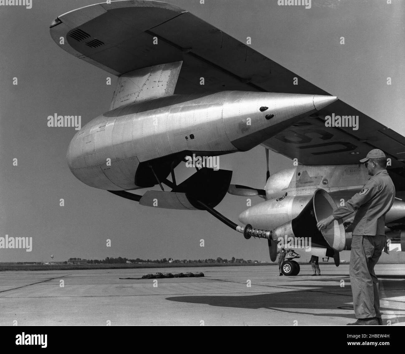 US military airplane mechanic putting refueling cone into wing pod ...