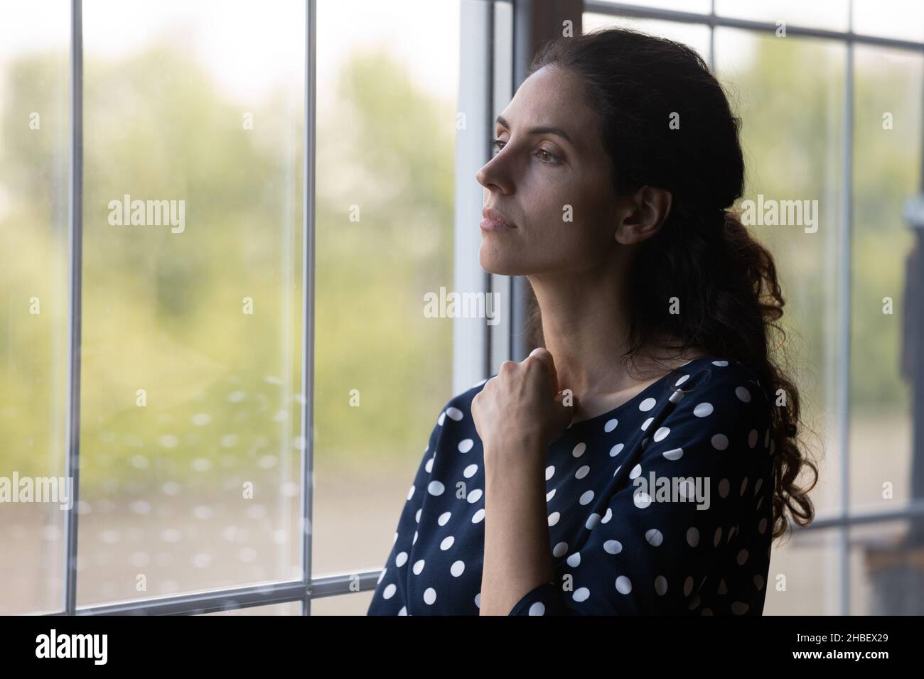 Pensive millennial woman looking out of window Stock Photo - Alamy