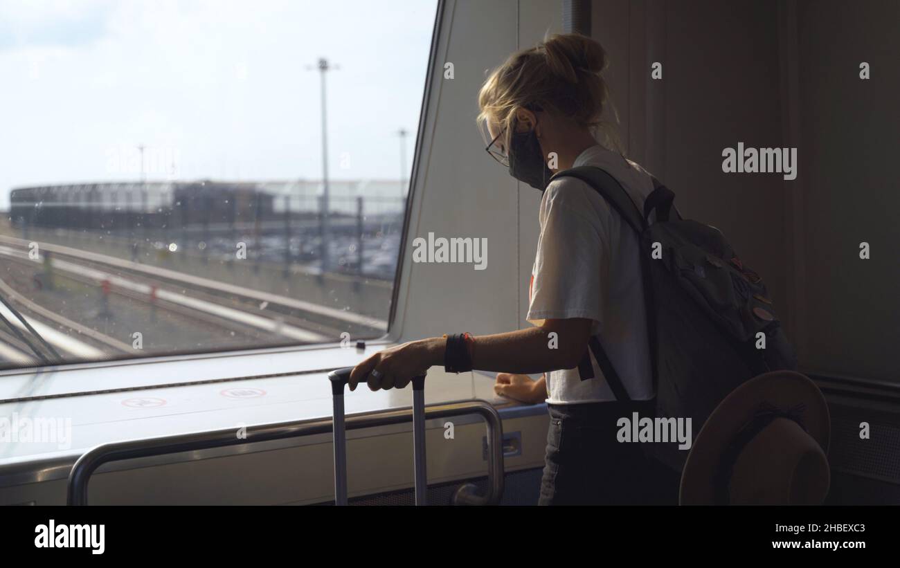 Pretty woman traveler wearing face mask on the way to airport terminal ...