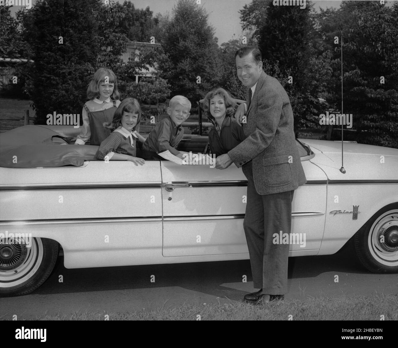 Family of 5, Mom, Dad and 3 children pause to look at the camera while ...