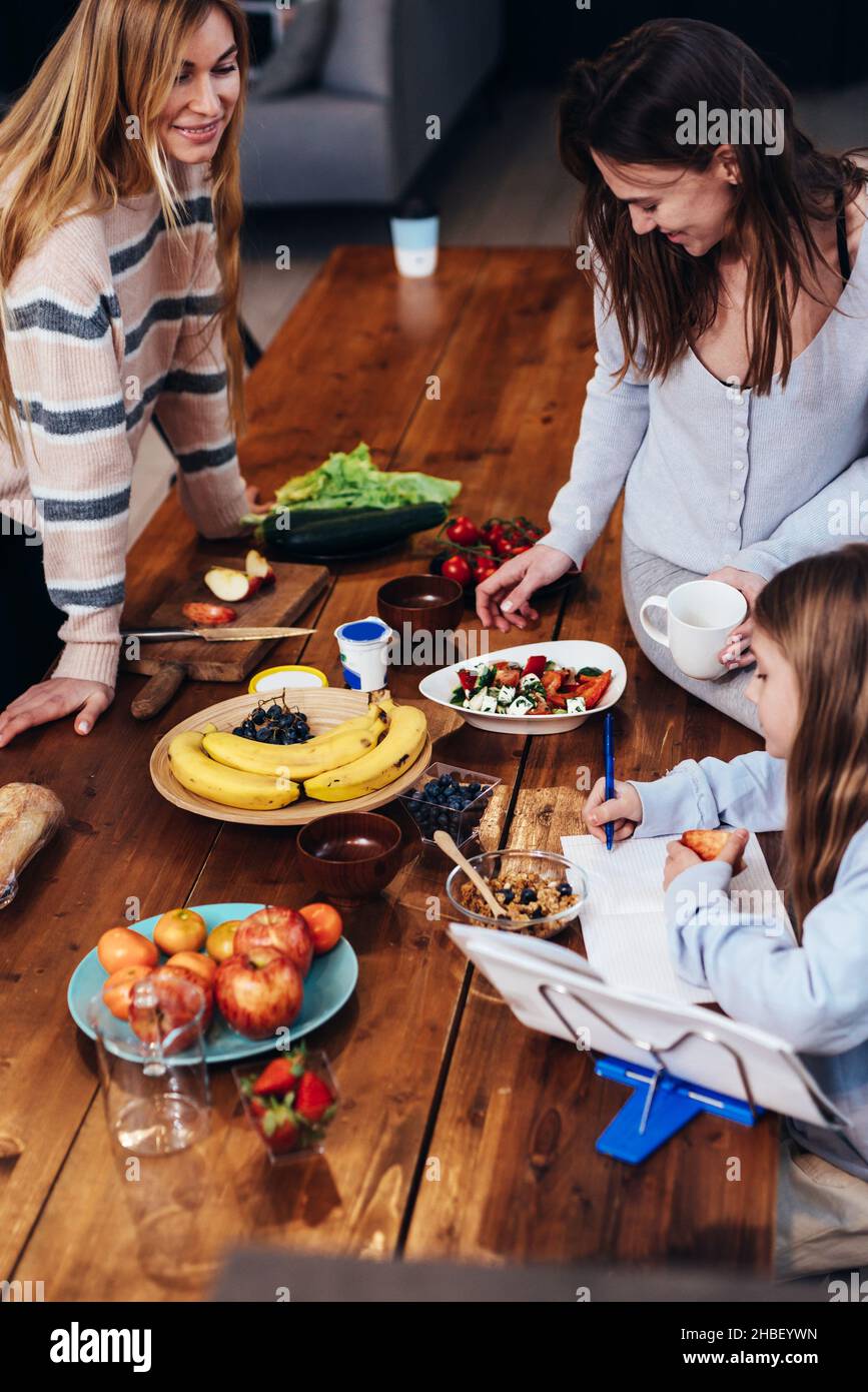 Young women set the table, girl does her homework Stock Photo - Alamy