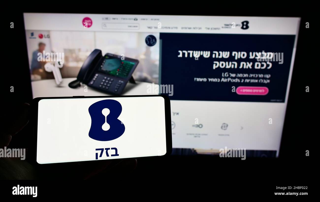 Person holding smartphone with logo of Bezeq The Israeli ...