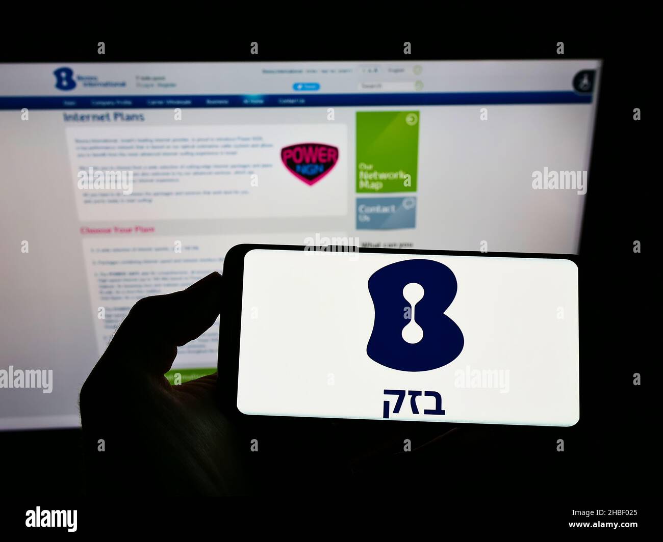 Person holding mobile phone with logo of Bezeq The Israeli ...