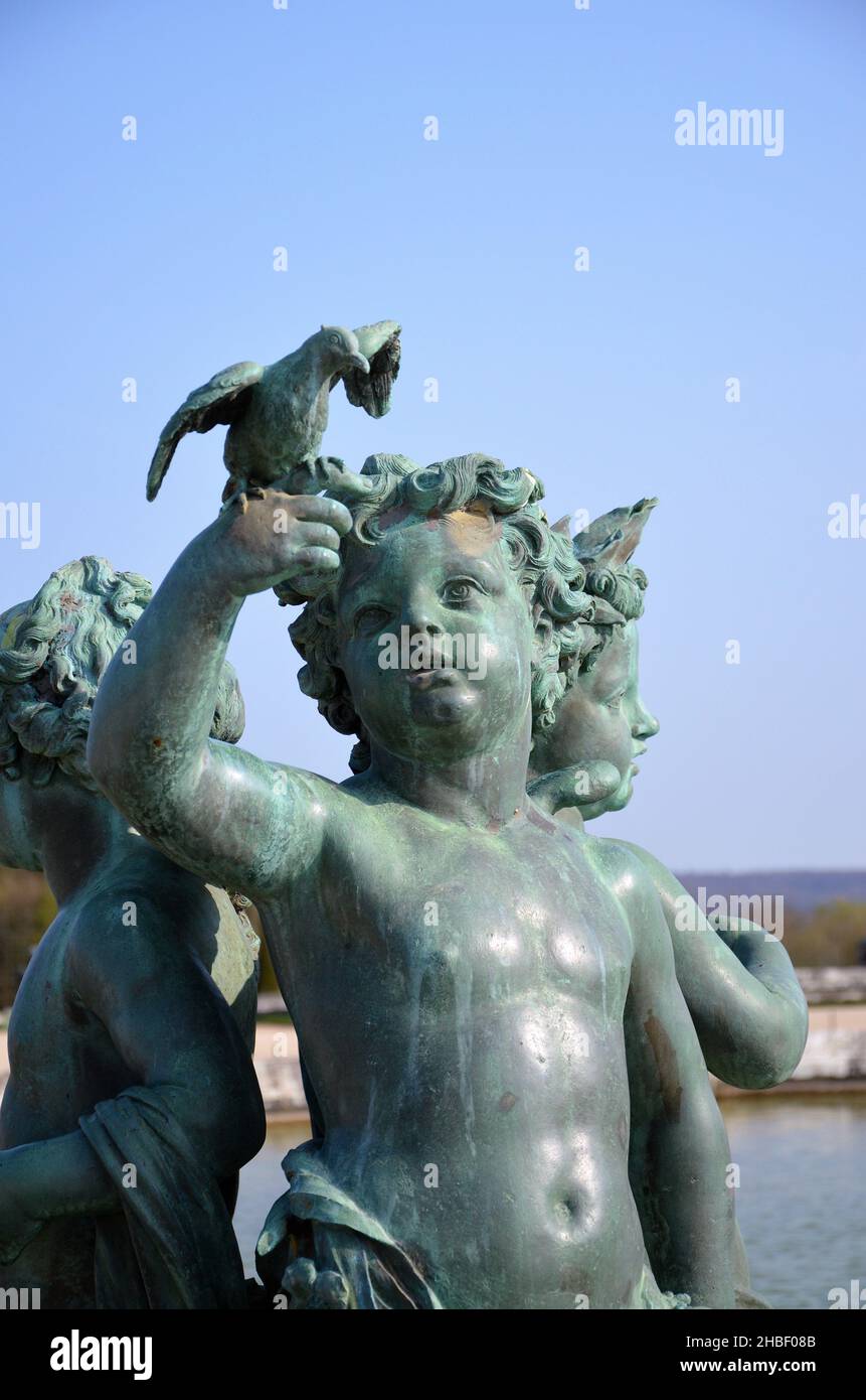 Bronze statue of three cherubs on the edge of a basin of the Bassin du ...