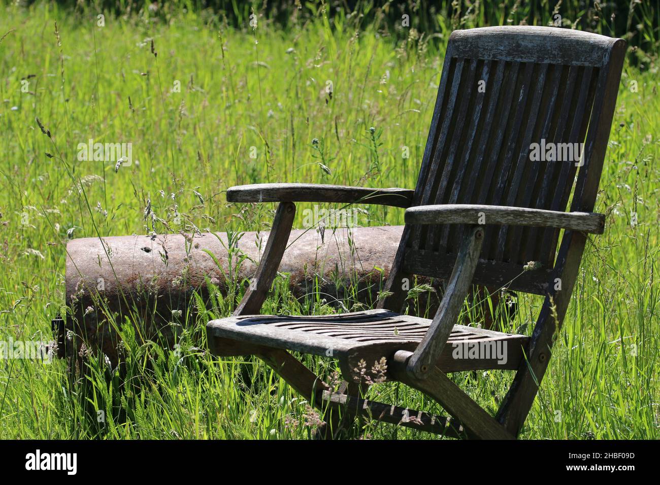 Traditional wooden seat in a garden on a long grass lawn with a ...