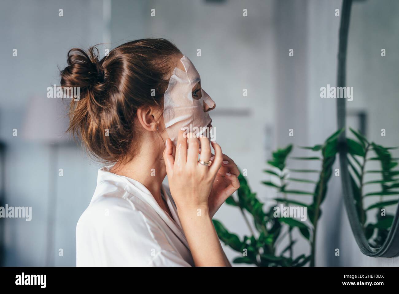 Woman grooming her face in the bathroom with a mask on her face in ...