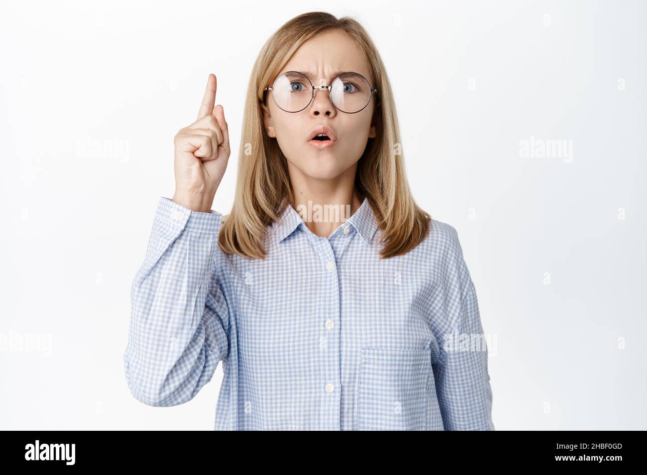 Cute clever blond girl, little kid in glasses and shirt, raising finger ...