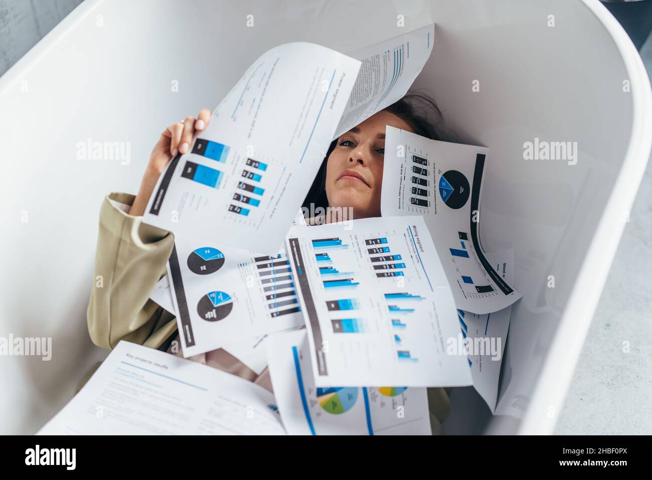 Woman is swamped with work, with a lot of paper, documents piled on top ...