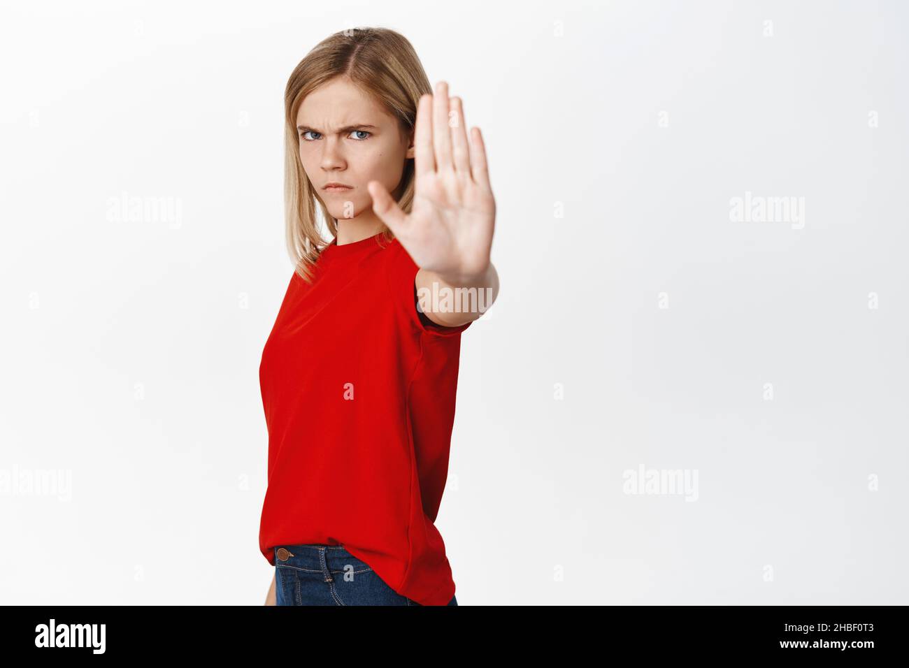 Serious little kid, girl extends one hand, shows stop, taboo or block ...