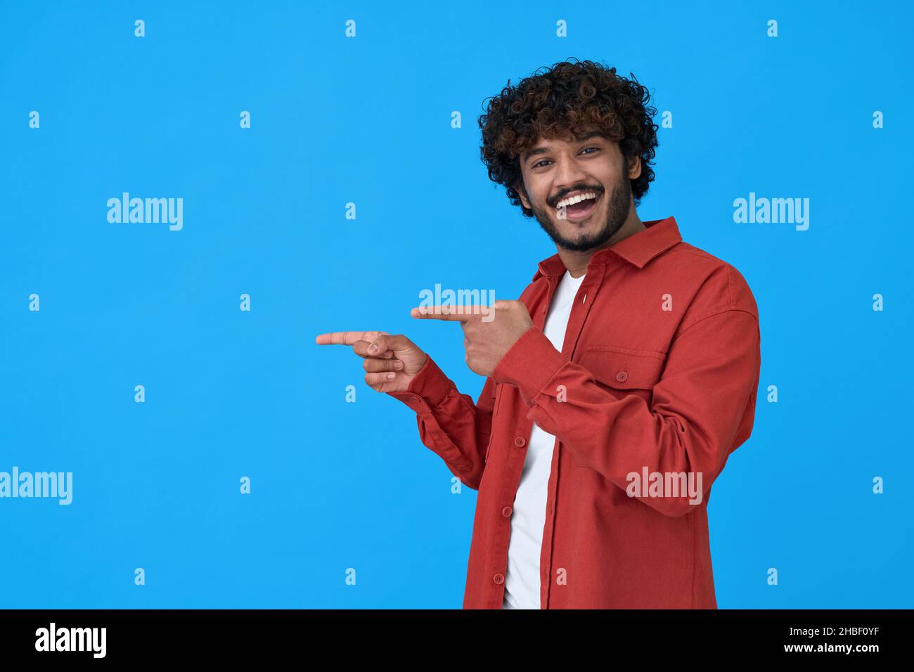 Happy excited young indian man pointing fingers on blue background ...
