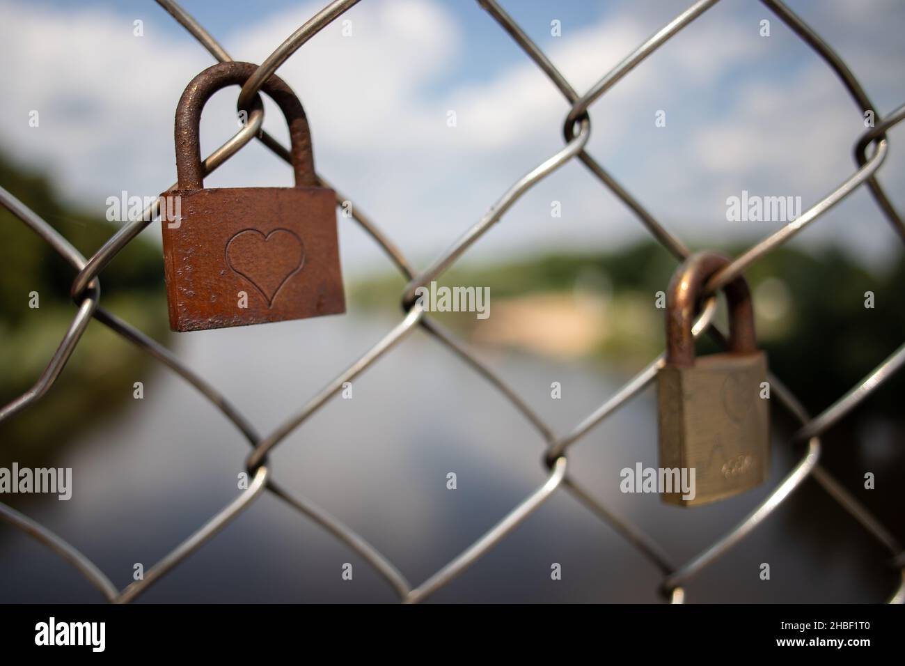 detail of rusty locks with a heart symbol on a fence symbolizing ...
