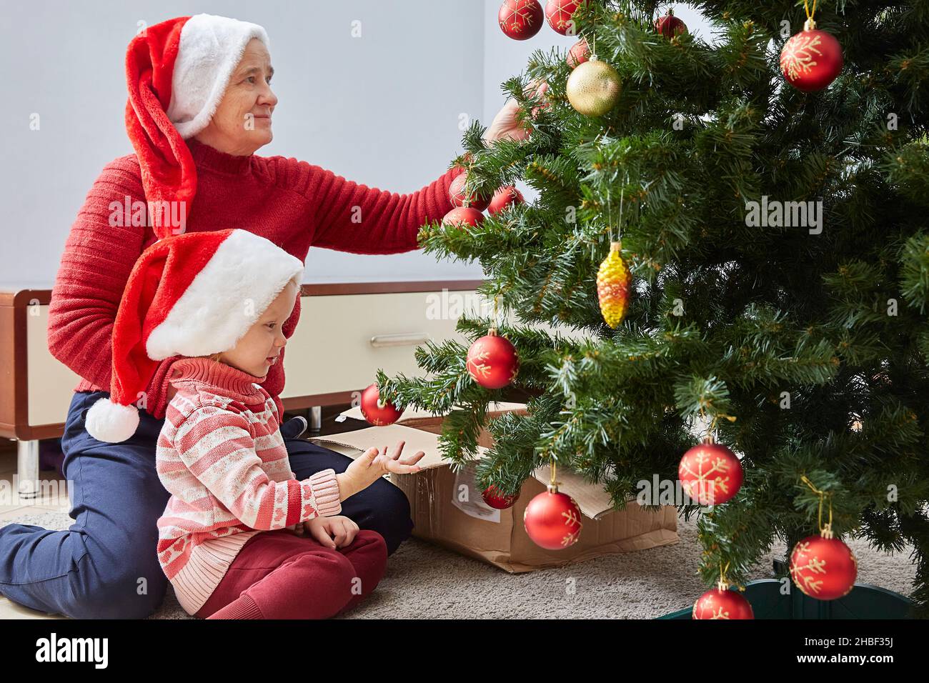 happy family of different generations decorate a Christmas tree in the ...