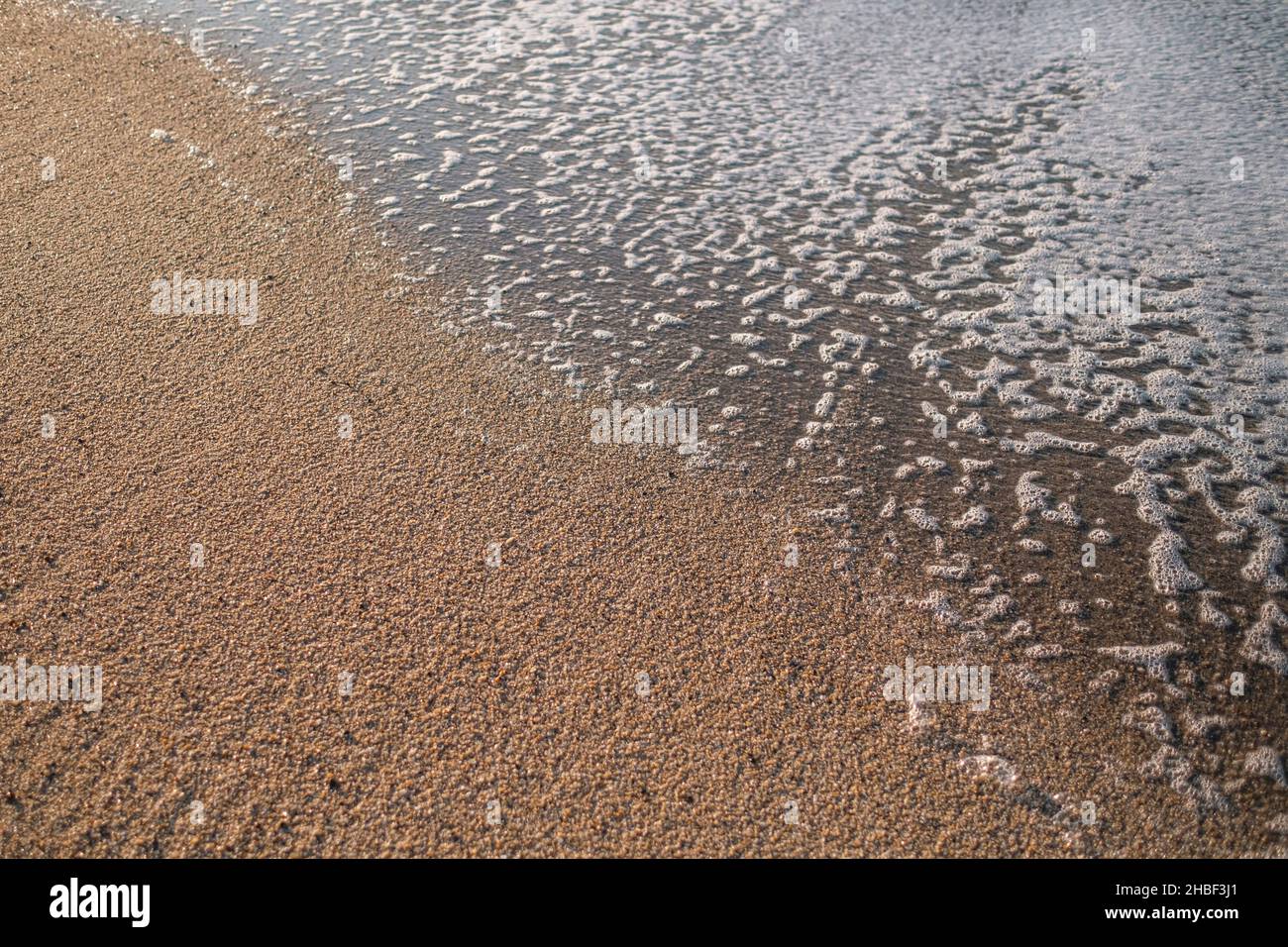 The beach sand texture with the foam of the surf close-up Stock Photo ...