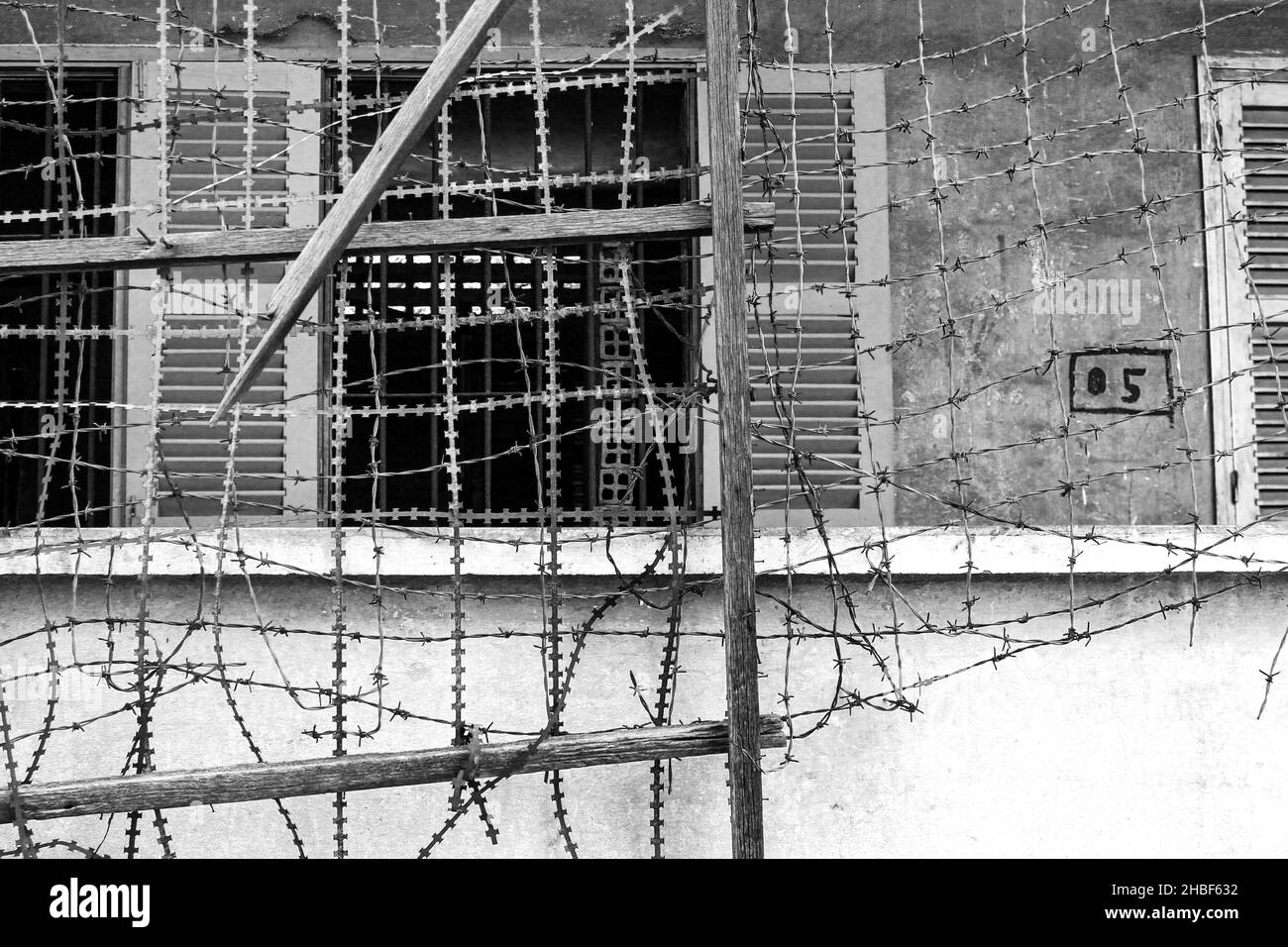 A grayscale of a facade of a building with windows from barbed wires ...