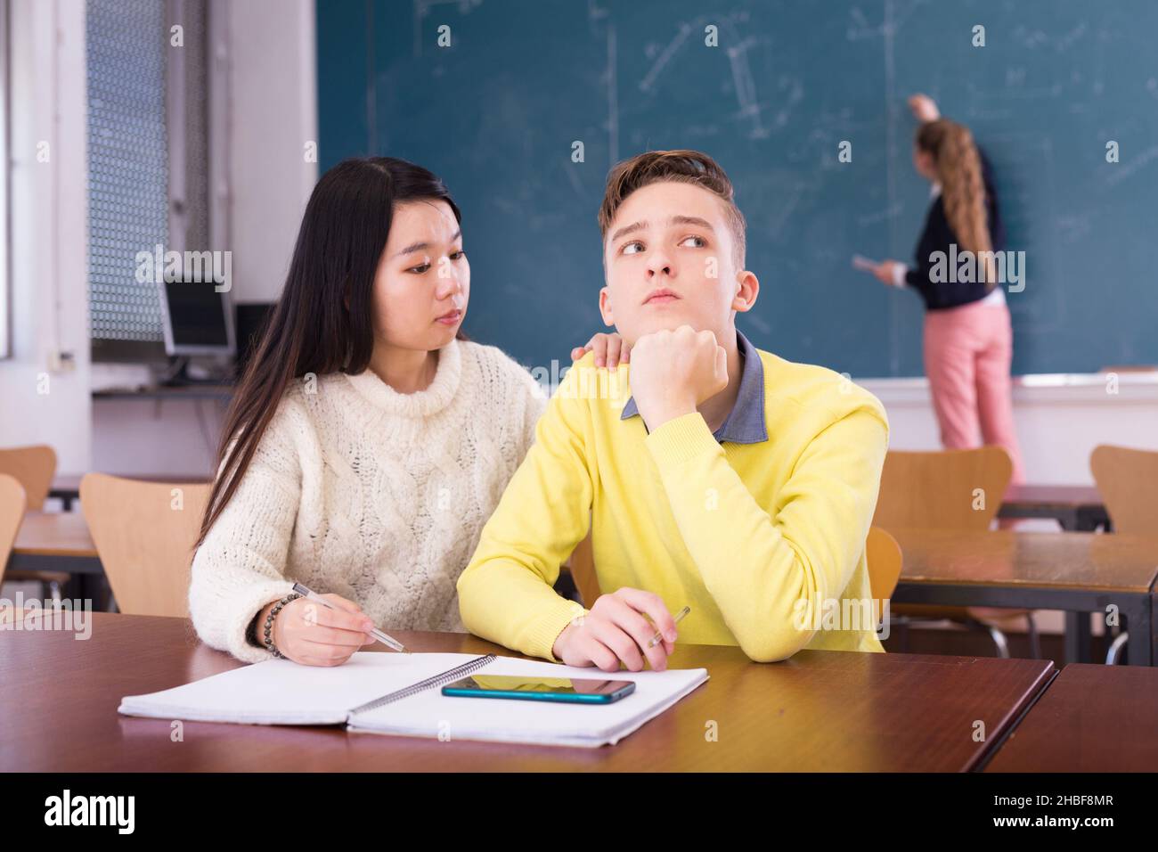 Chinese girl student explaining learning material to bored classmate ...