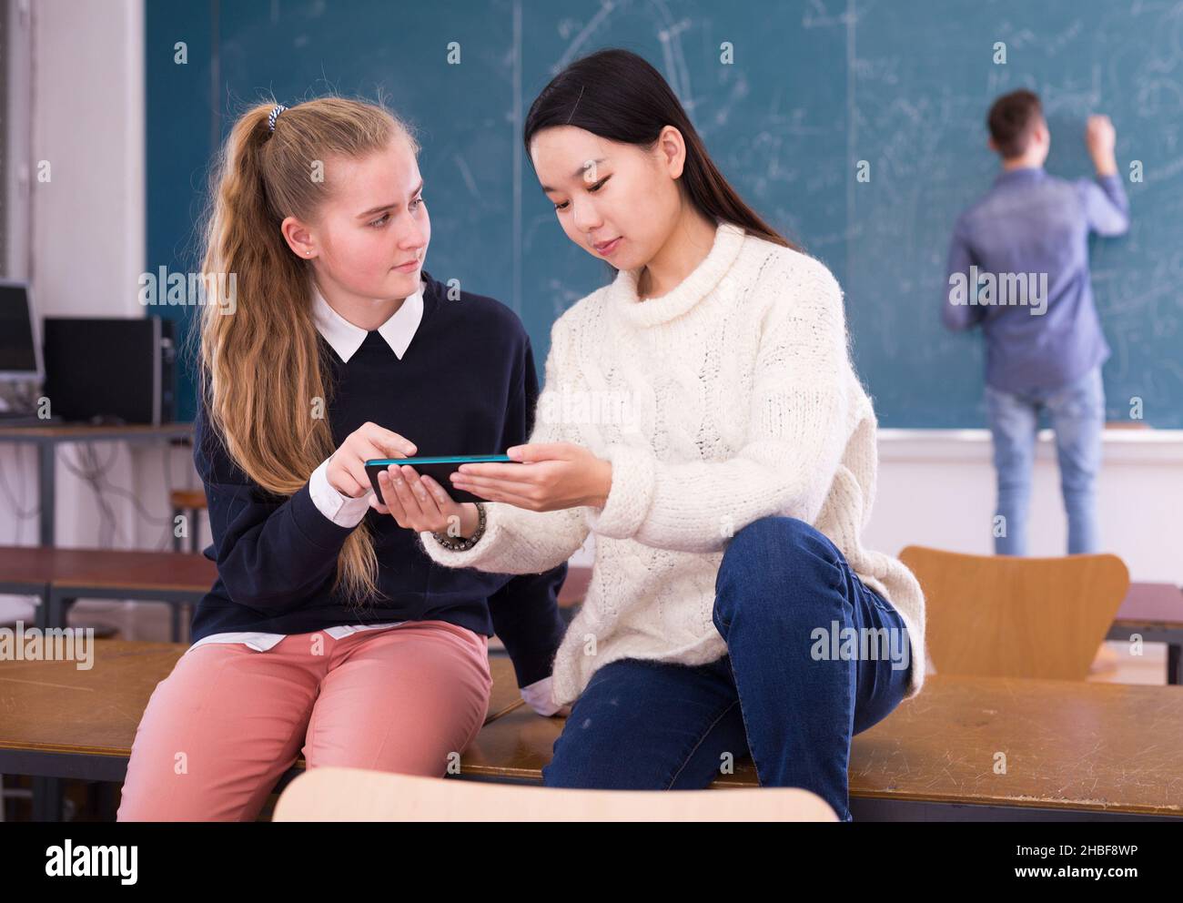 Female students talking and using smartphone during break Stock Photo ...