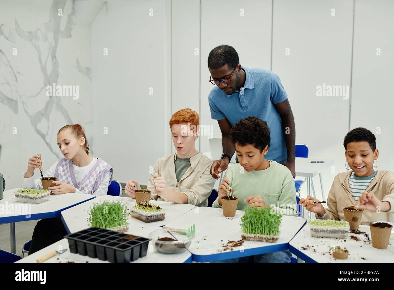 Diverse group of children planting seeds while experimenting at biology ...