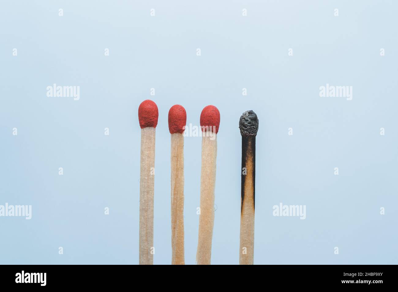 A closeup of four matches and a used one aligned with isolated blue ...