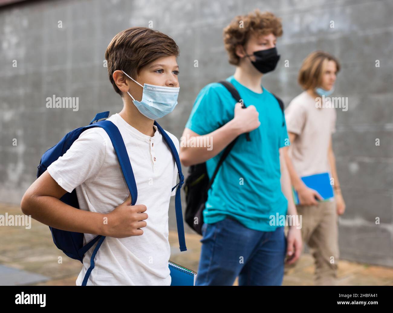 Schoolboys of different ages in face mask walking near school Stock ...