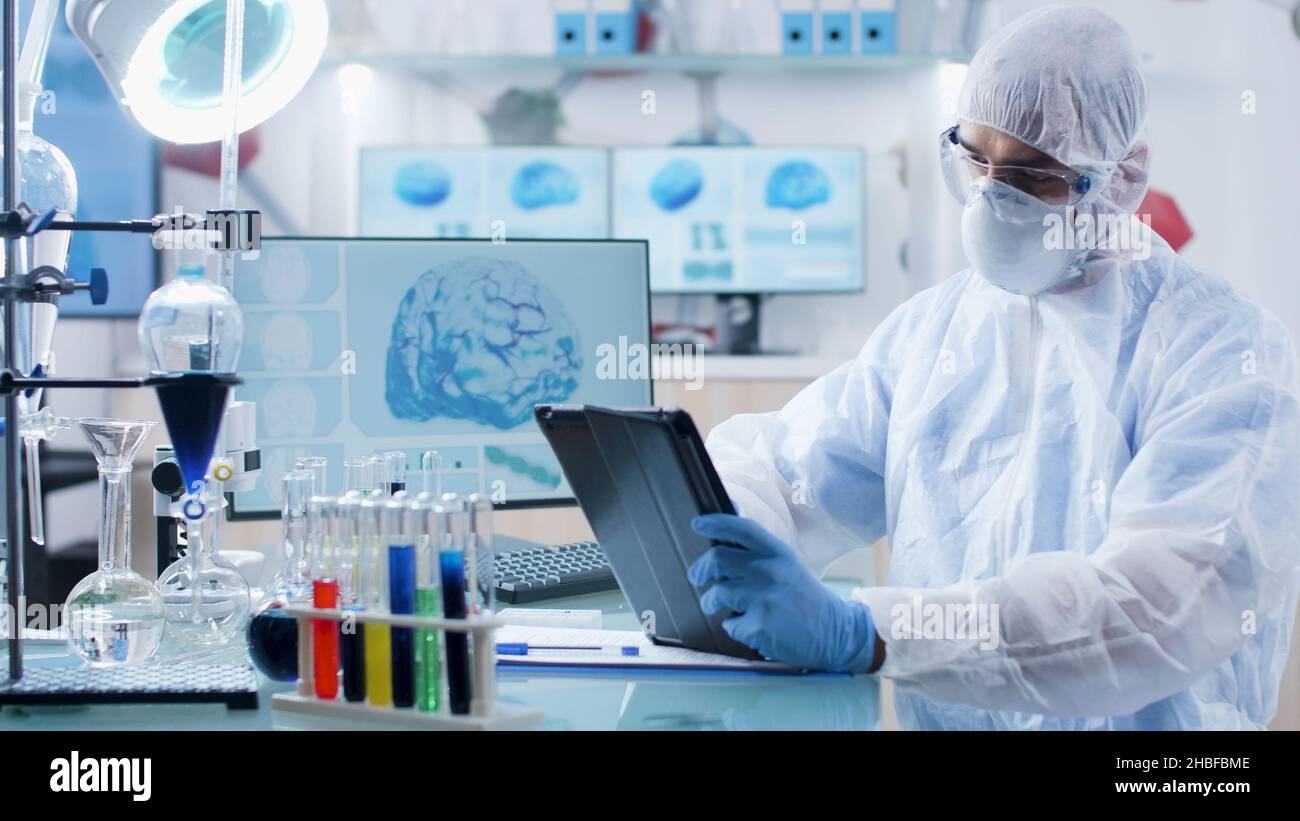 Doctor researcher with ppe equipment holding tablet computer analyzing ...