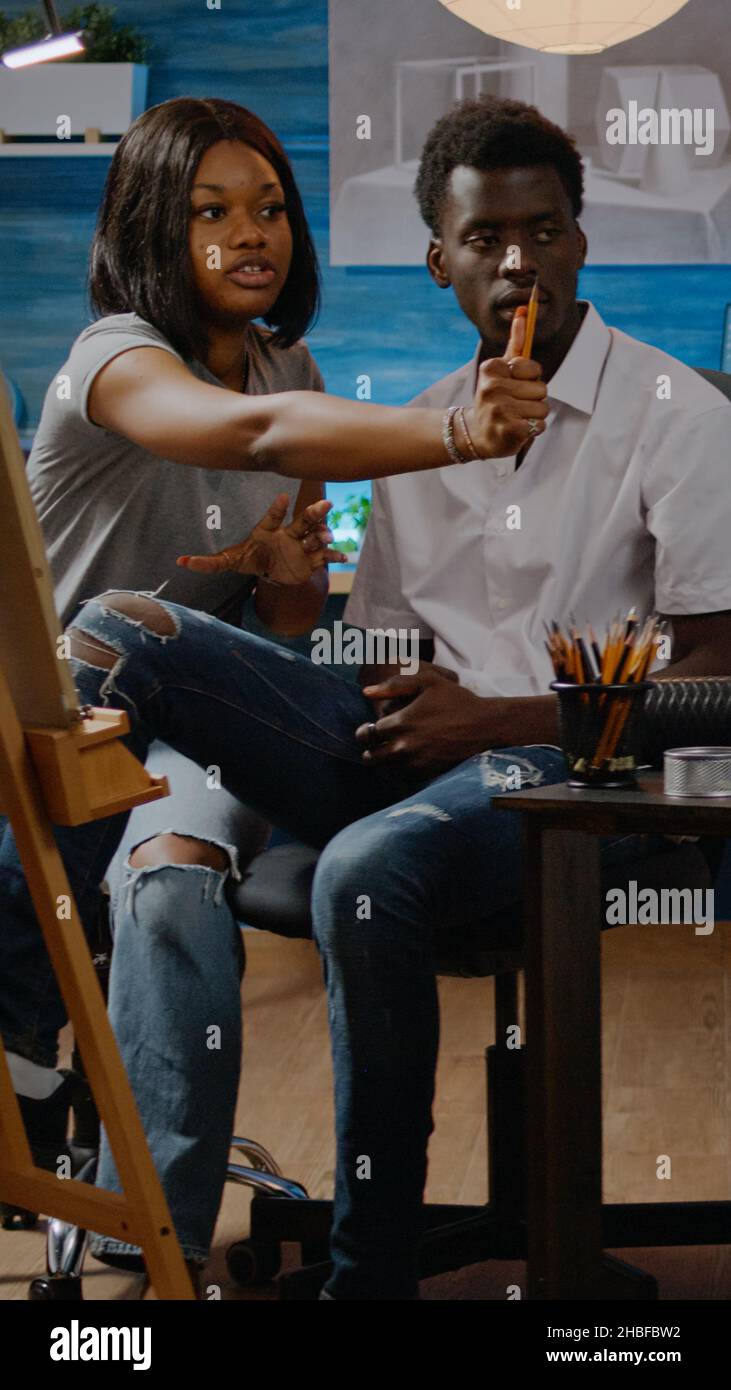 African american couple of artists looking at vase design and drawing ...