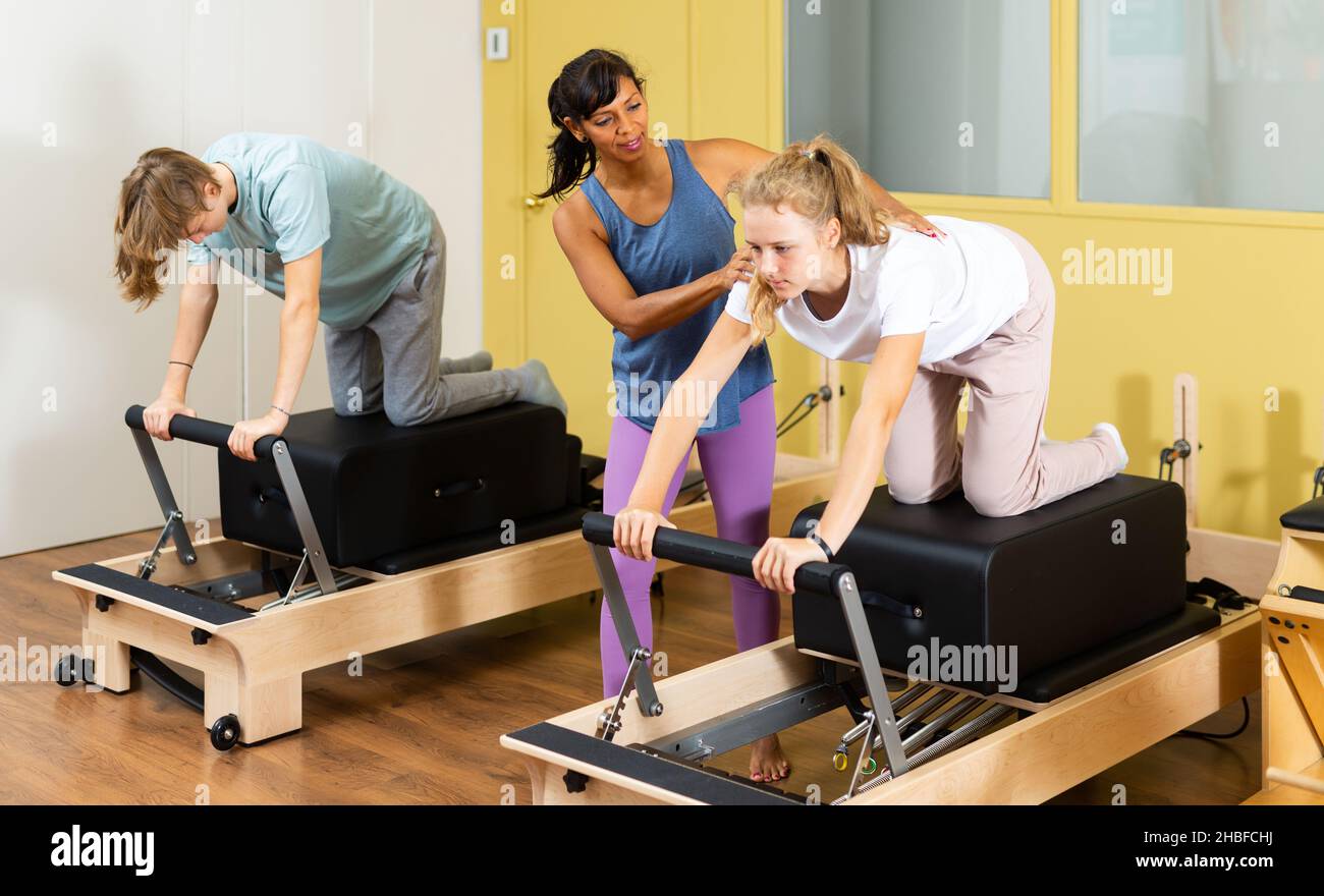 Professional trainer helps an teen boy and girl in pilates class Stock ...