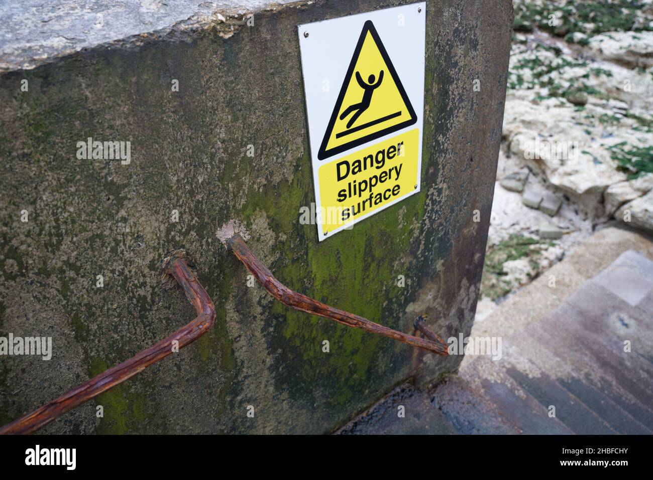 A danger sign stuck on an old stone wall covered in moss Stock Photo ...