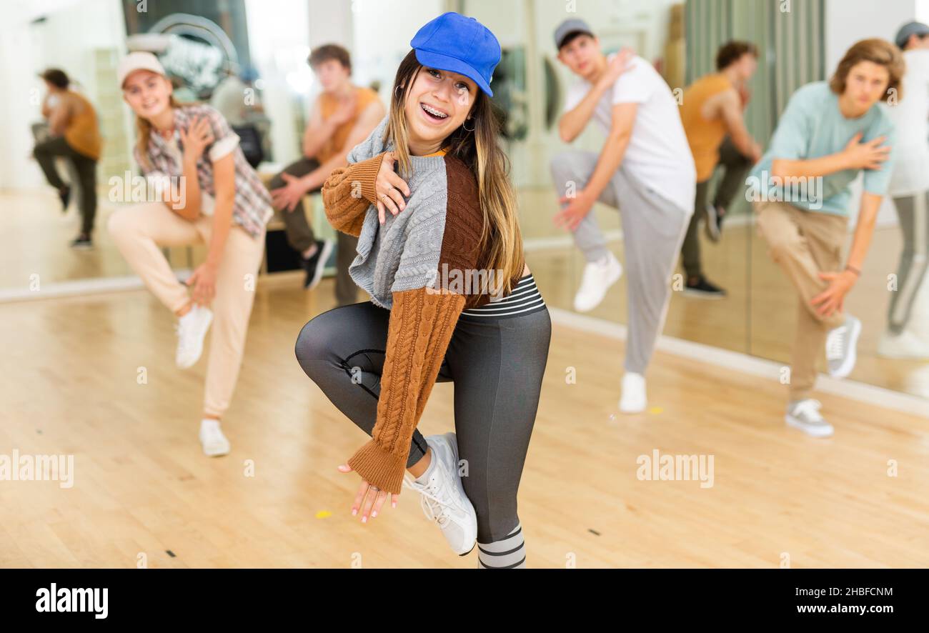 Cheerful hispanic teenage girl practicing hip-hop movements in studio ...