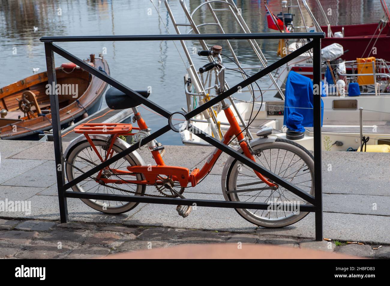 Orange Cycle parked up against railings at Honfleur, France Stock Photo ...