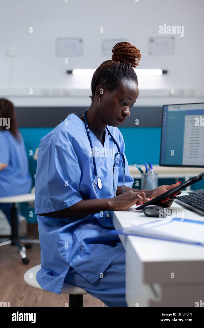African american woman nurse checking sickness expertise using tablet ...
