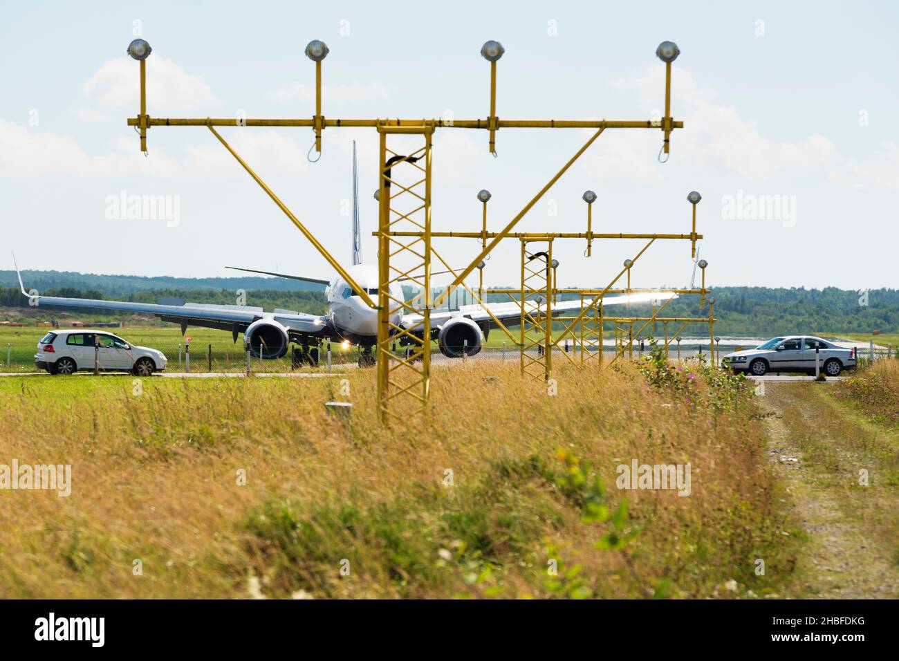 A Boeing 737 has landed on a small airport, a road with cars in ...