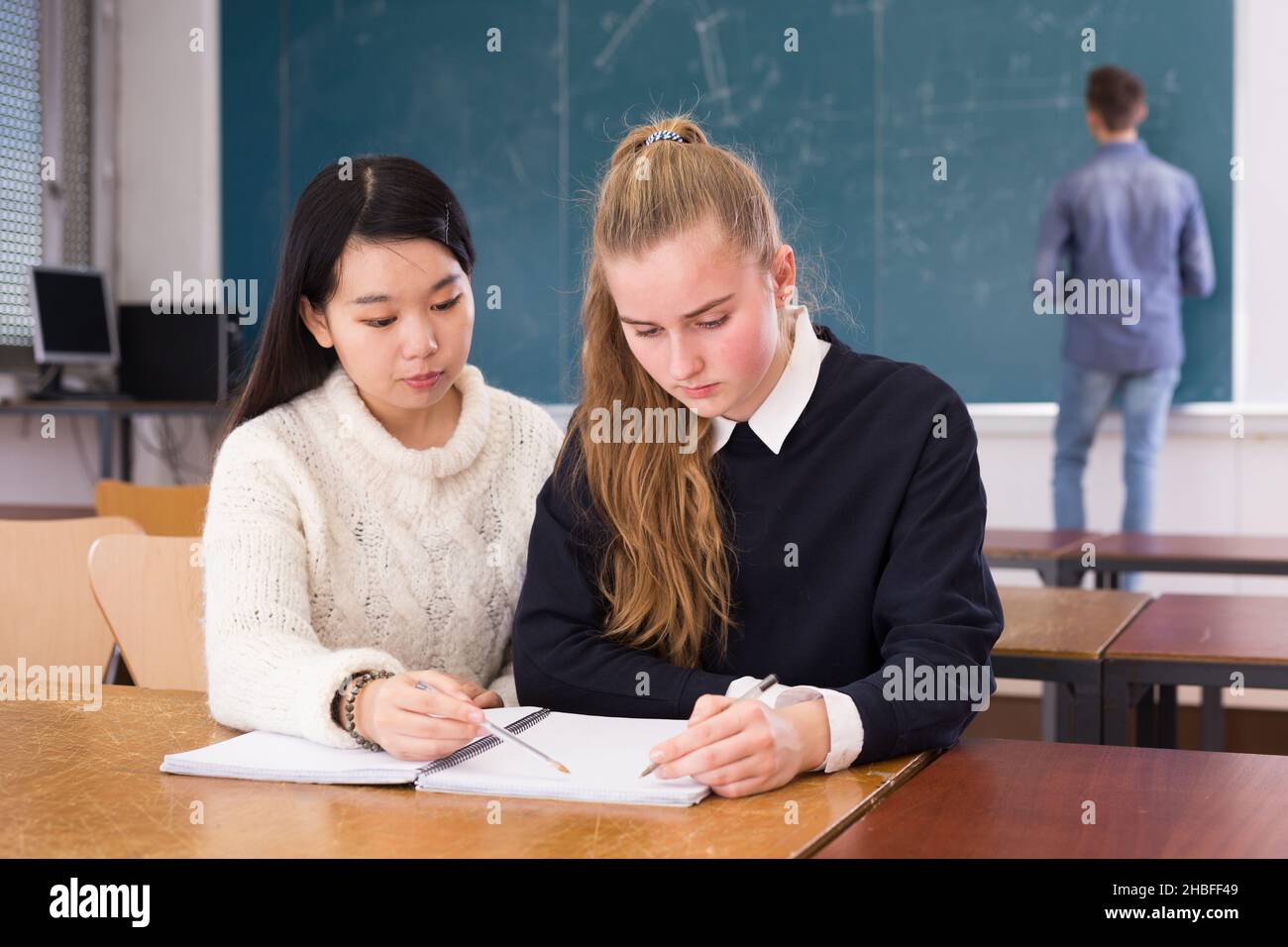 Asian teen girl explaining study material to female classmate Stock ...