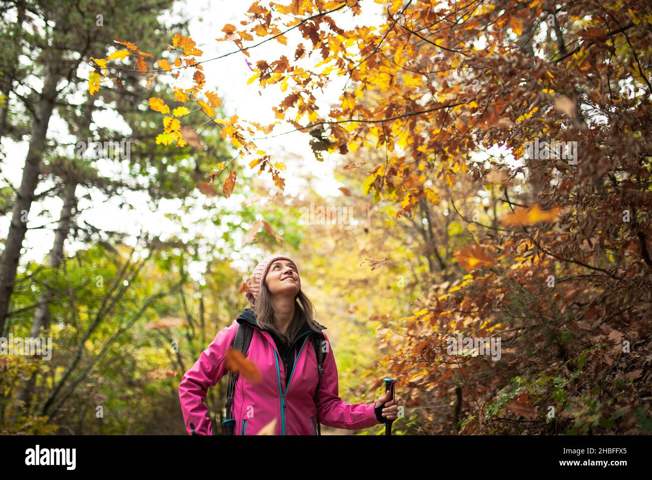 Hiking girl in pink on a trail in the forest. Looking up enjoying the ...