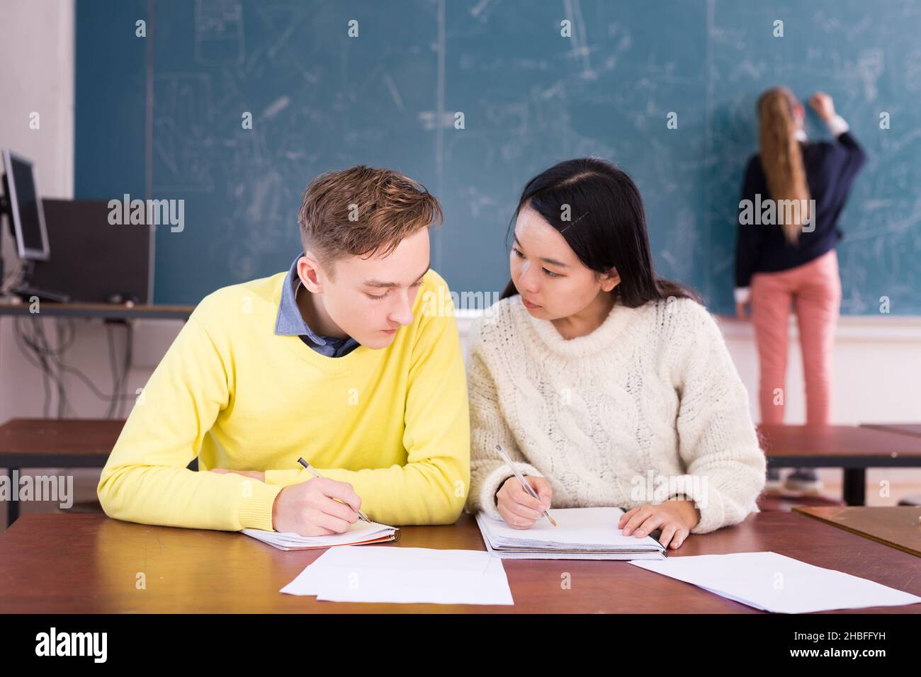 Chinese girl and male students writing notes together Stock Photo - Alamy