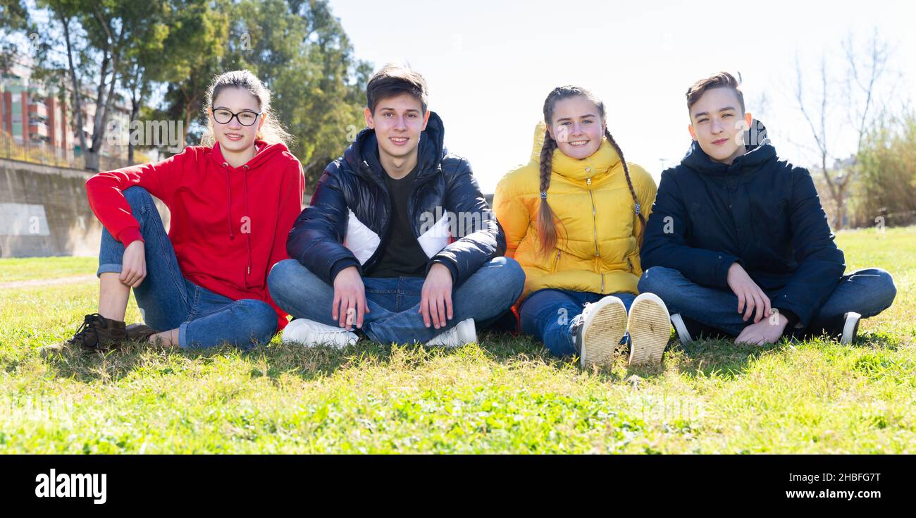 Happy teenagers sitting on green lawn Stock Photo - Alamy