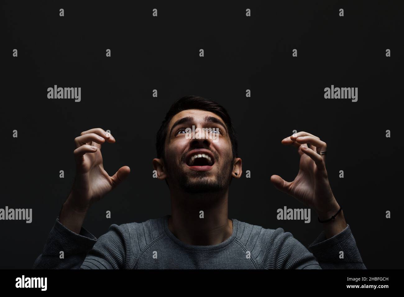 Portrait of young surprised male with beard. Hands up. Looking up Stock ...