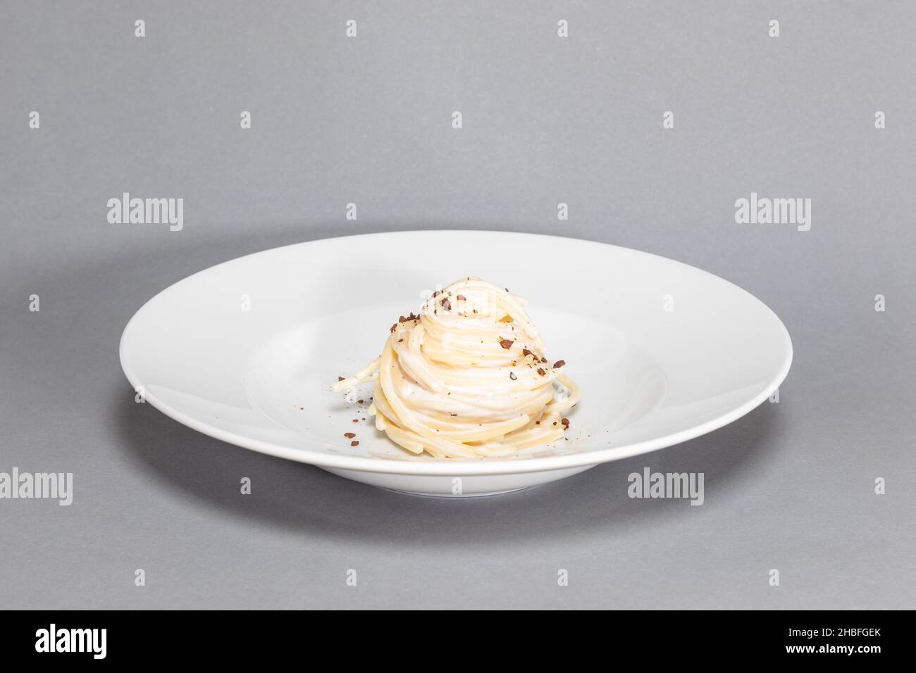 A closeup shot of a delisous vegan pasta dish on a white plate on a ...