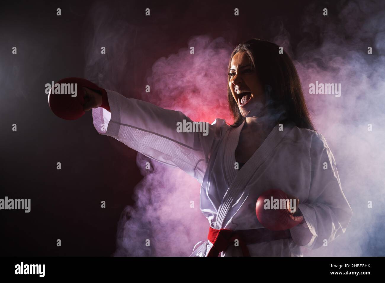girl exercising karate punch against red fog background Stock Photo - Alamy