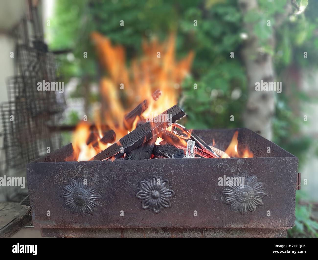 Blue flame on a rusty barbecue on background of green leaves Stock ...