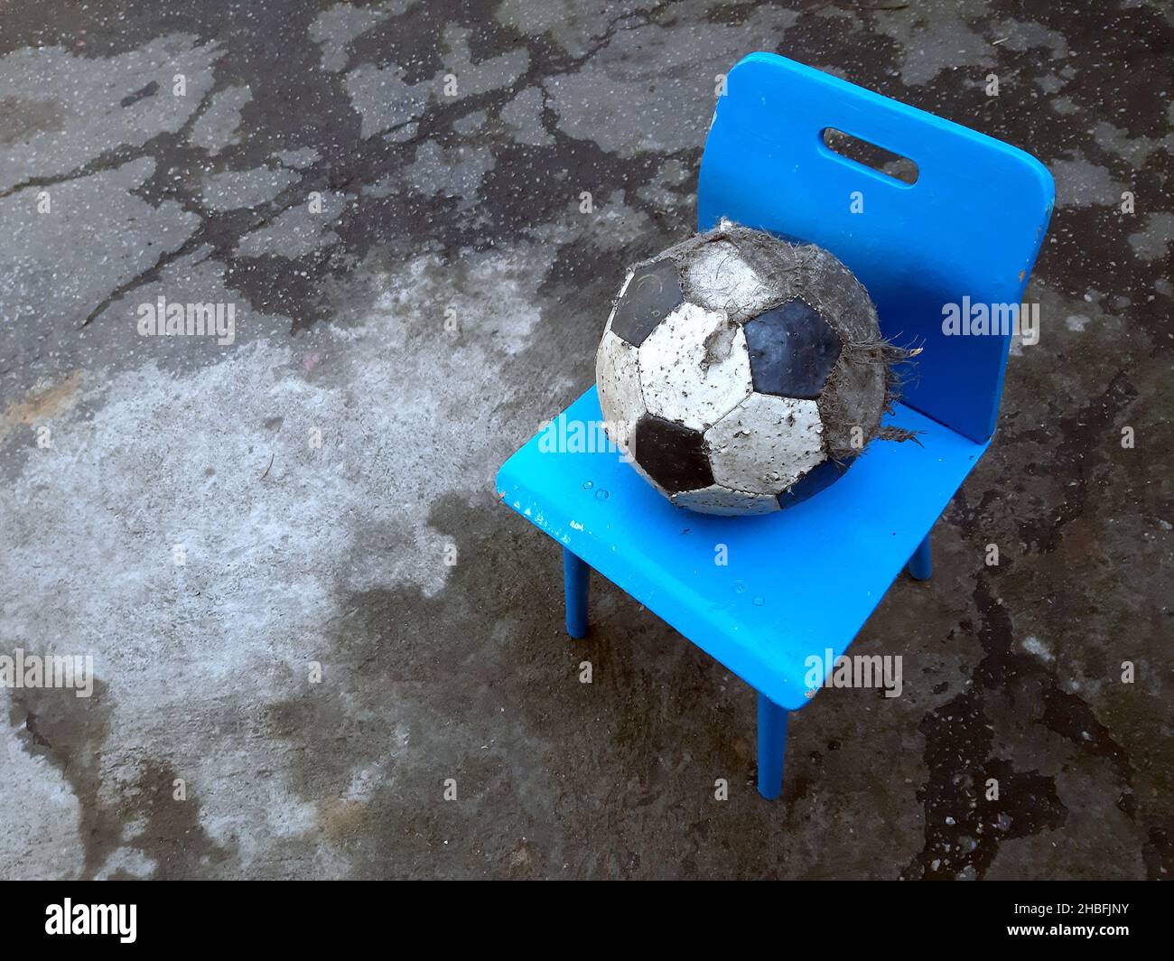 A disheveled soccer ball lies on a small children's chair in yard on ...