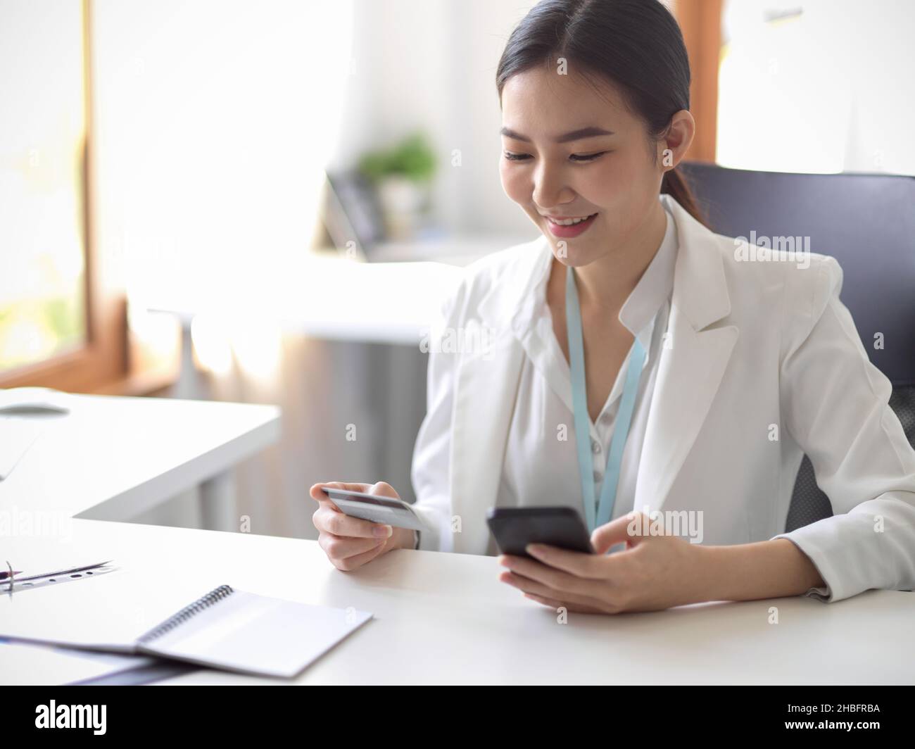 A gorgeous Asian businesswoman uses mobile banking to transfer money or ...
