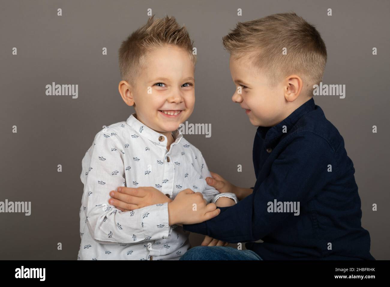 Two brothers hugging each other in front of a grey background Stock ...