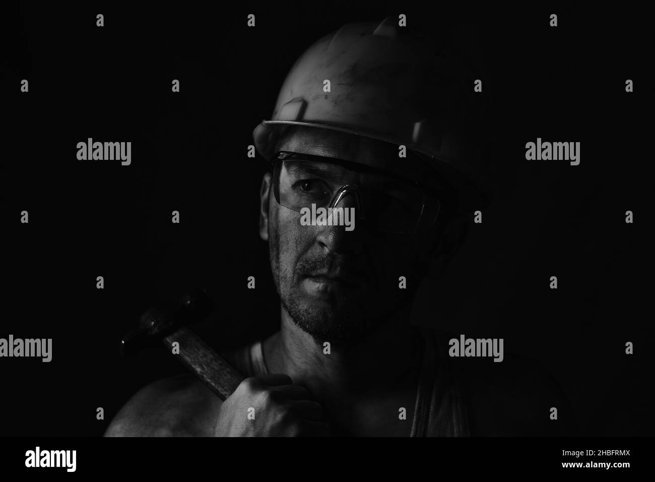Miner, dirty in coal soot, wearing helmet, protective glasses and with ...