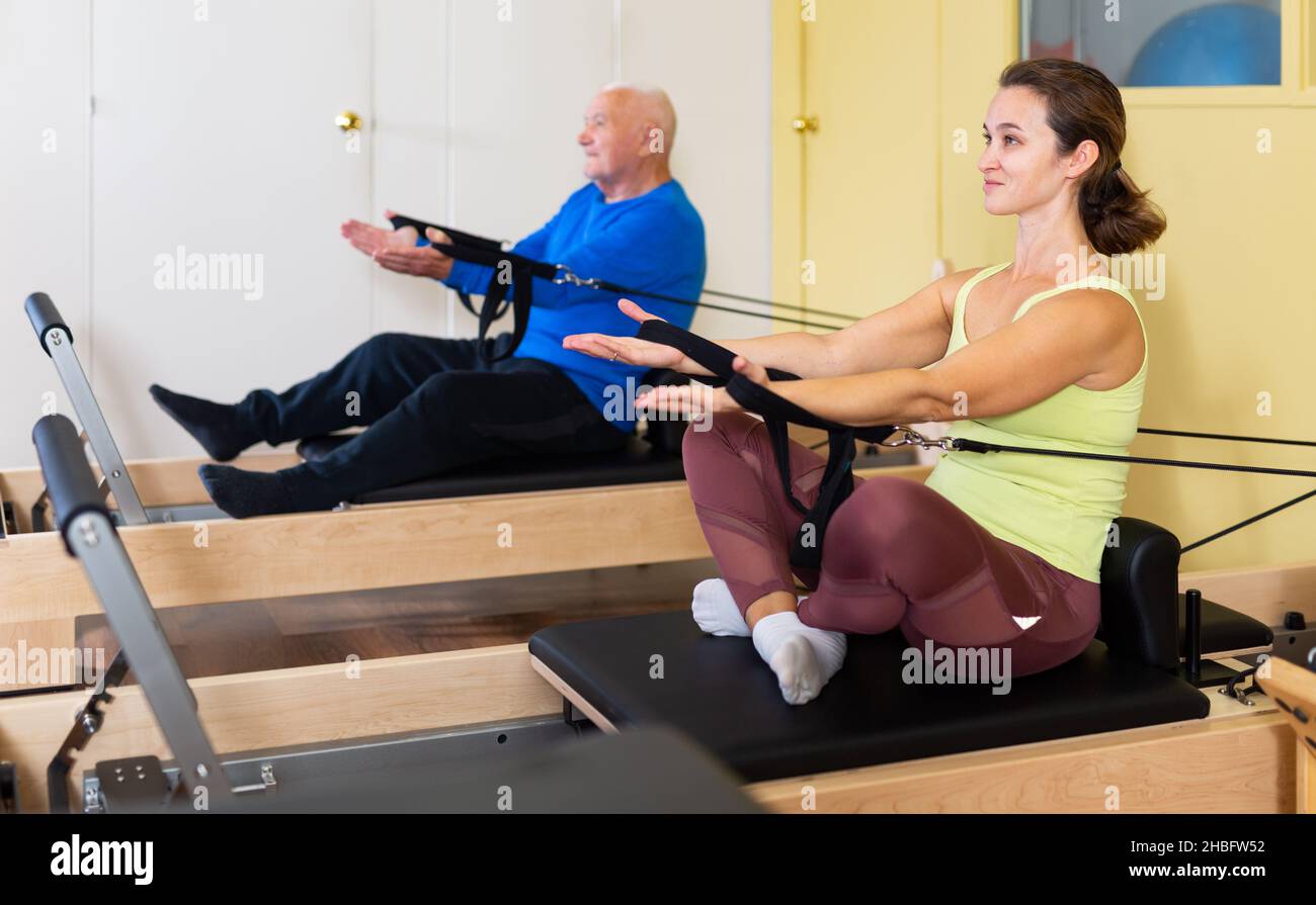 Woman performing pilates on reformer during group workout Stock Photo ...